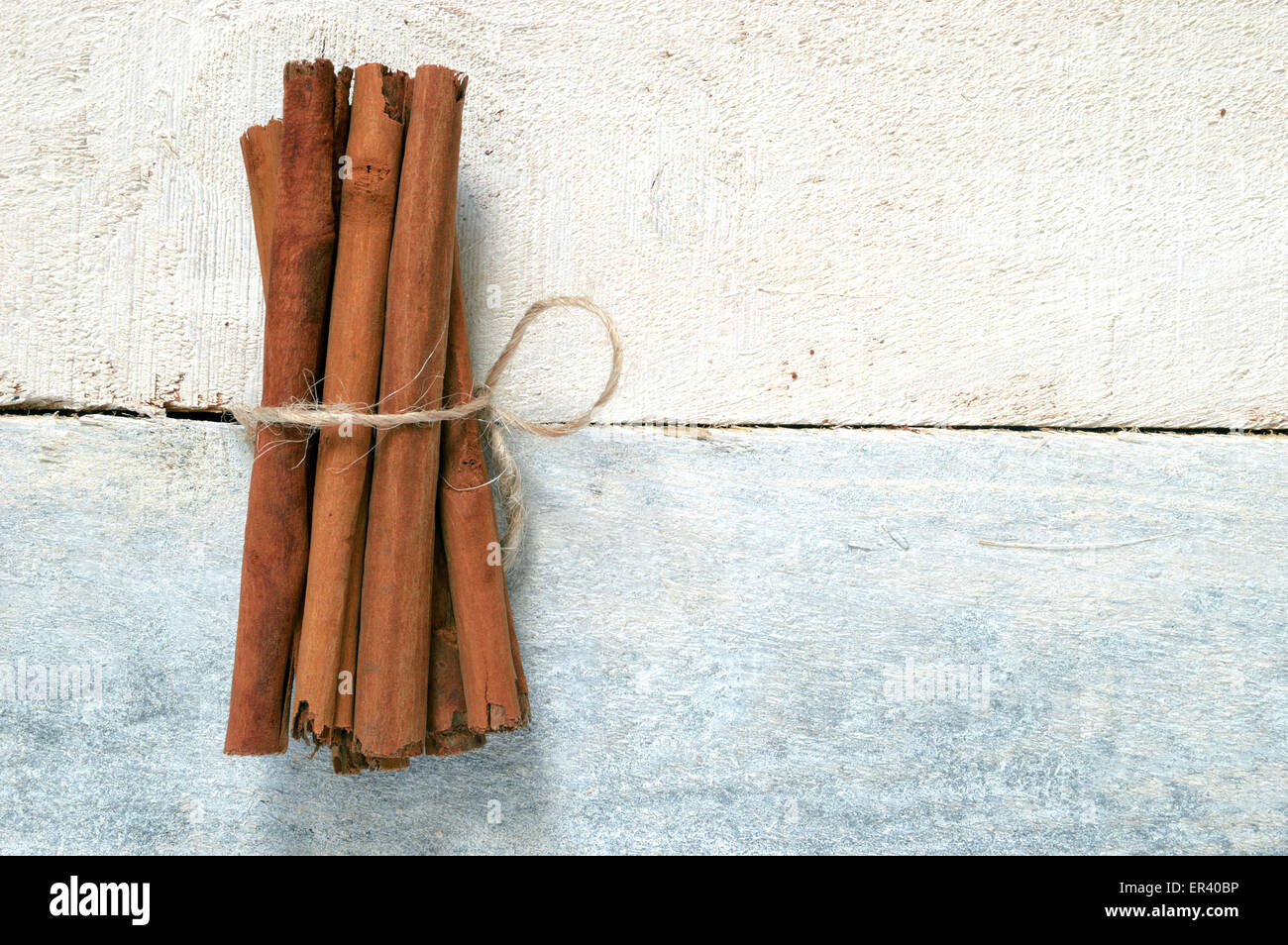 Some cinnamon sticks tied with a natural rope. All on a white wooden ...