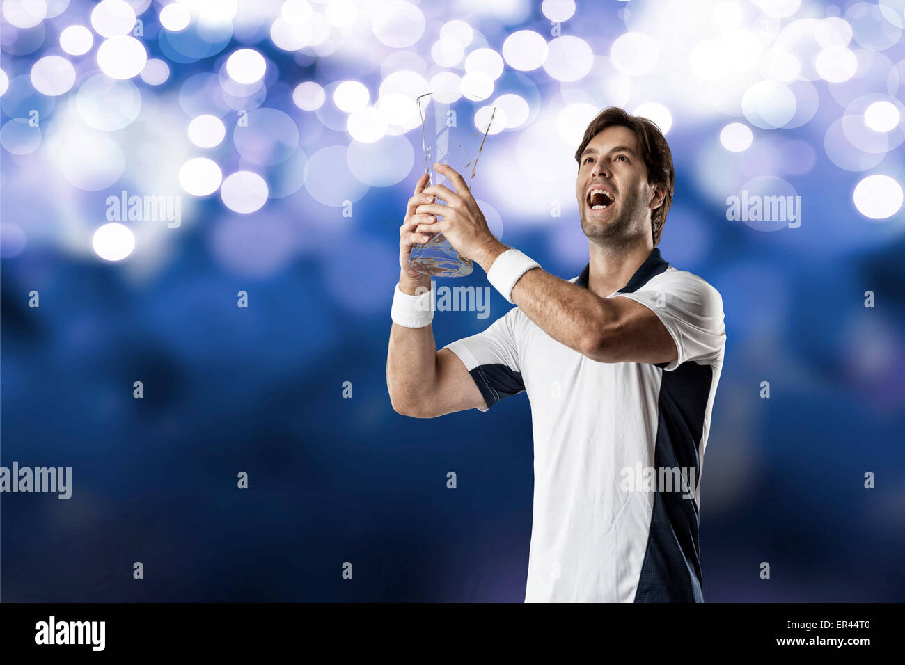 Tennis player celebrating with a glass trophy, on a blue lights ...