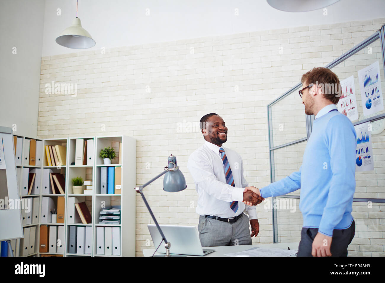 Young employer congratulating newly hired man Stock Photo - Alamy