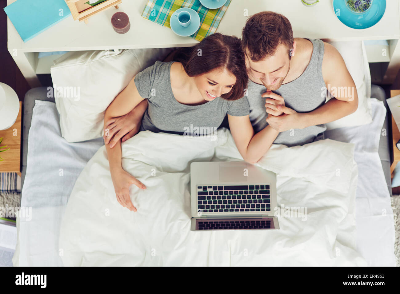 Young couple with laptop watching movie in bed Stock Photo - Alamy