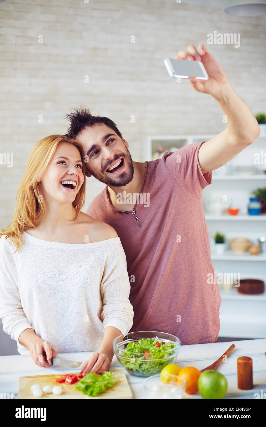 Affectionate couple making selfie while cooking food Stock Photo - Alamy