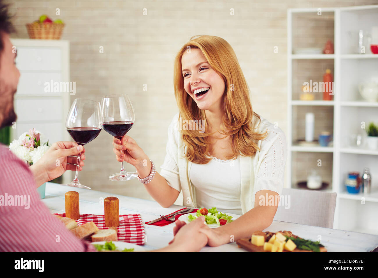 Happy young couple laughing while making toast by dinner table Stock ...