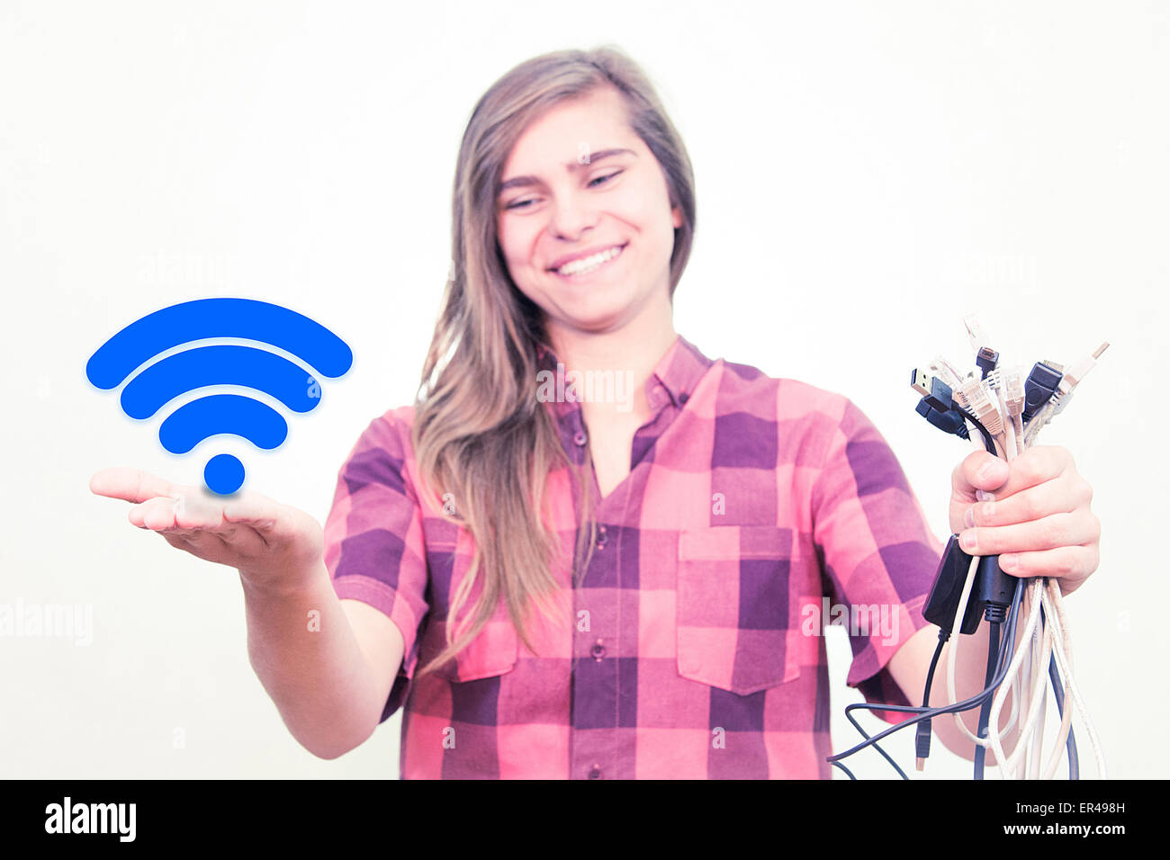 Young and happy girl is holding bunch of entangled cables in her hands ...