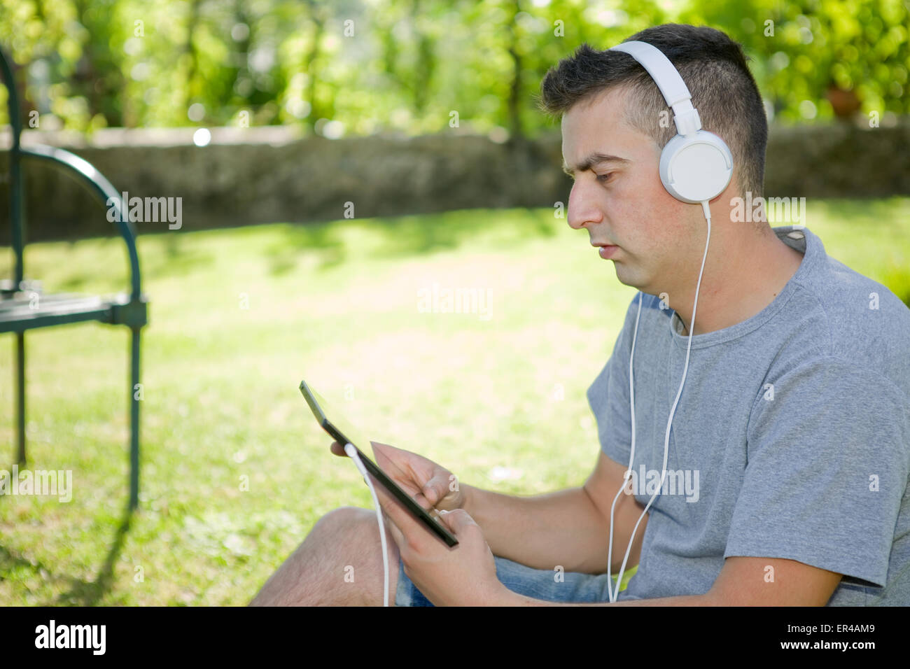 young man holding a tablet with headphones, outdoor Stock Photo - Alamy