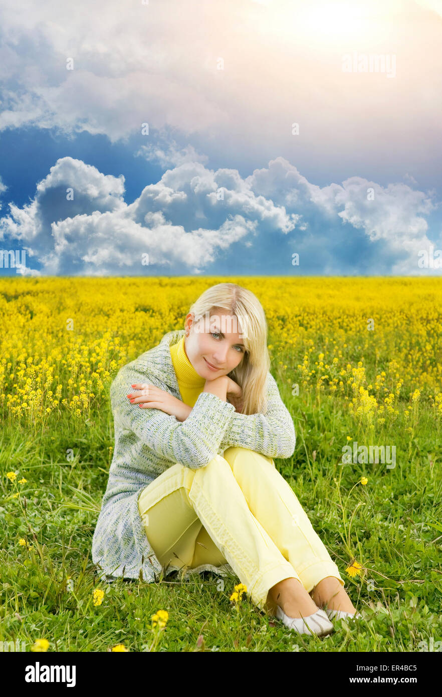 Beautiful young woman sitting in a flower field Stock Photo - Alamy