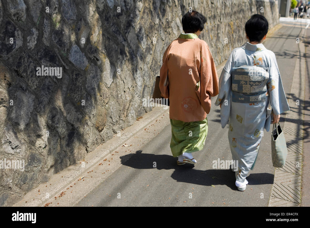 Two Japanese women walking along a path wearing traditional Kimono's in ...