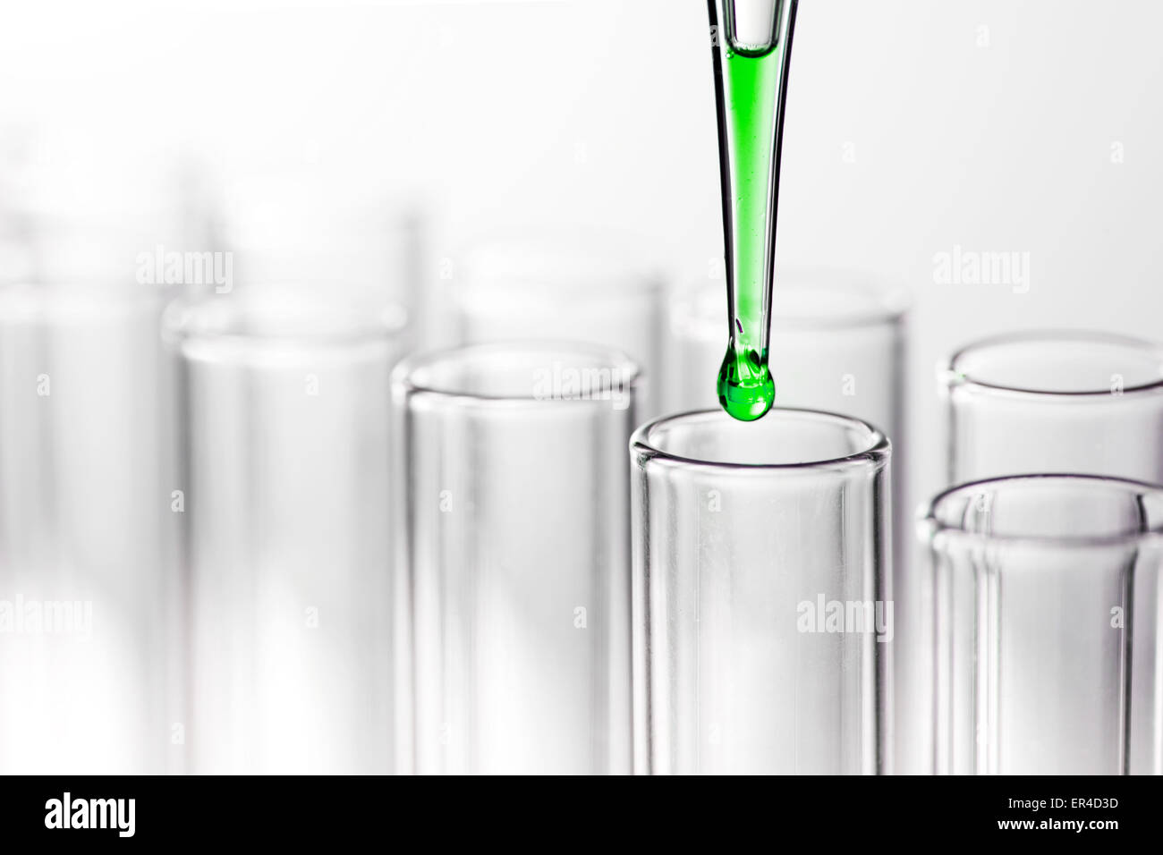 Laboratory pipette with drop of liquid over glass test tubes in a ...