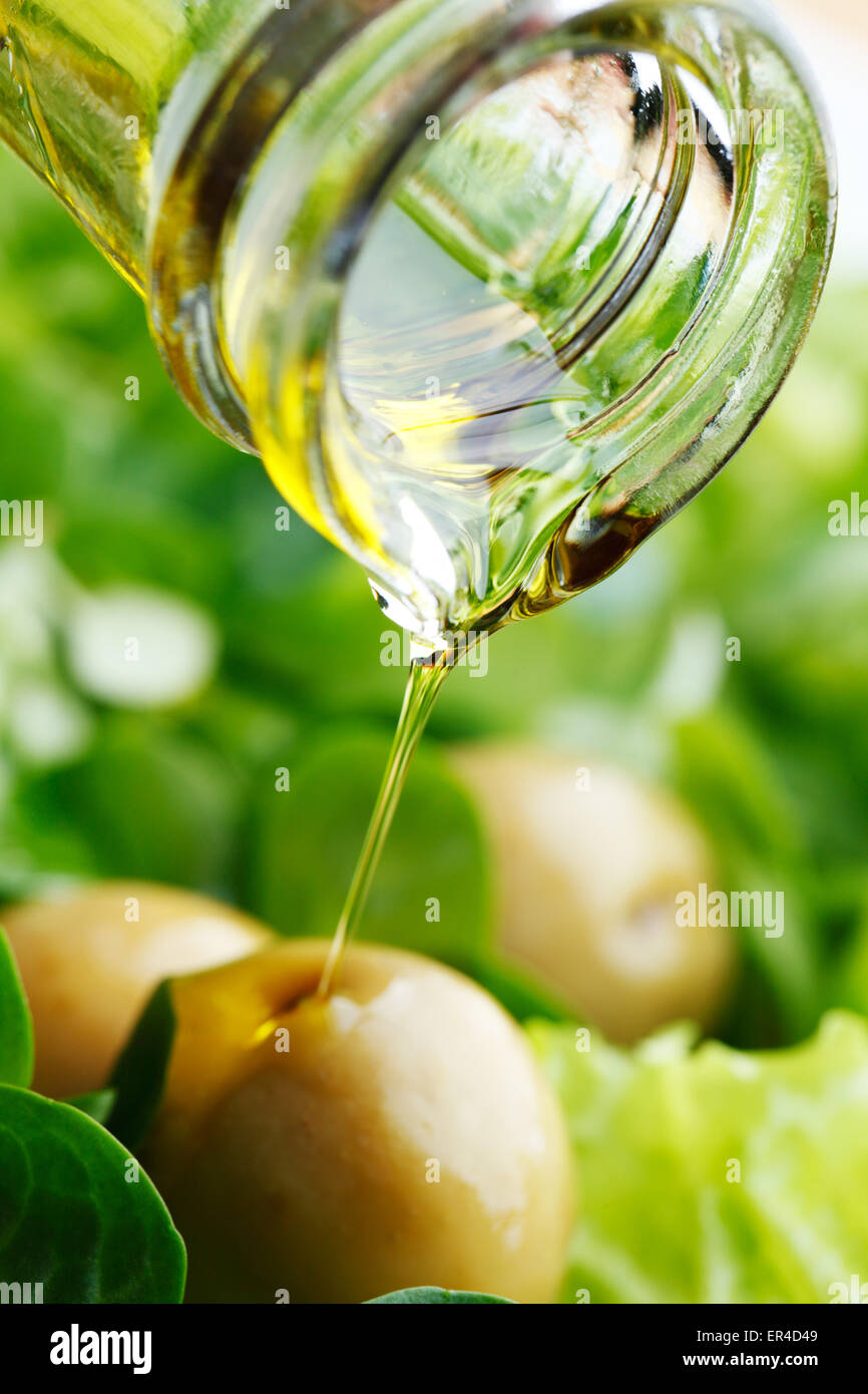 Pouring olive oil on corn salad with olives Stock Photo - Alamy