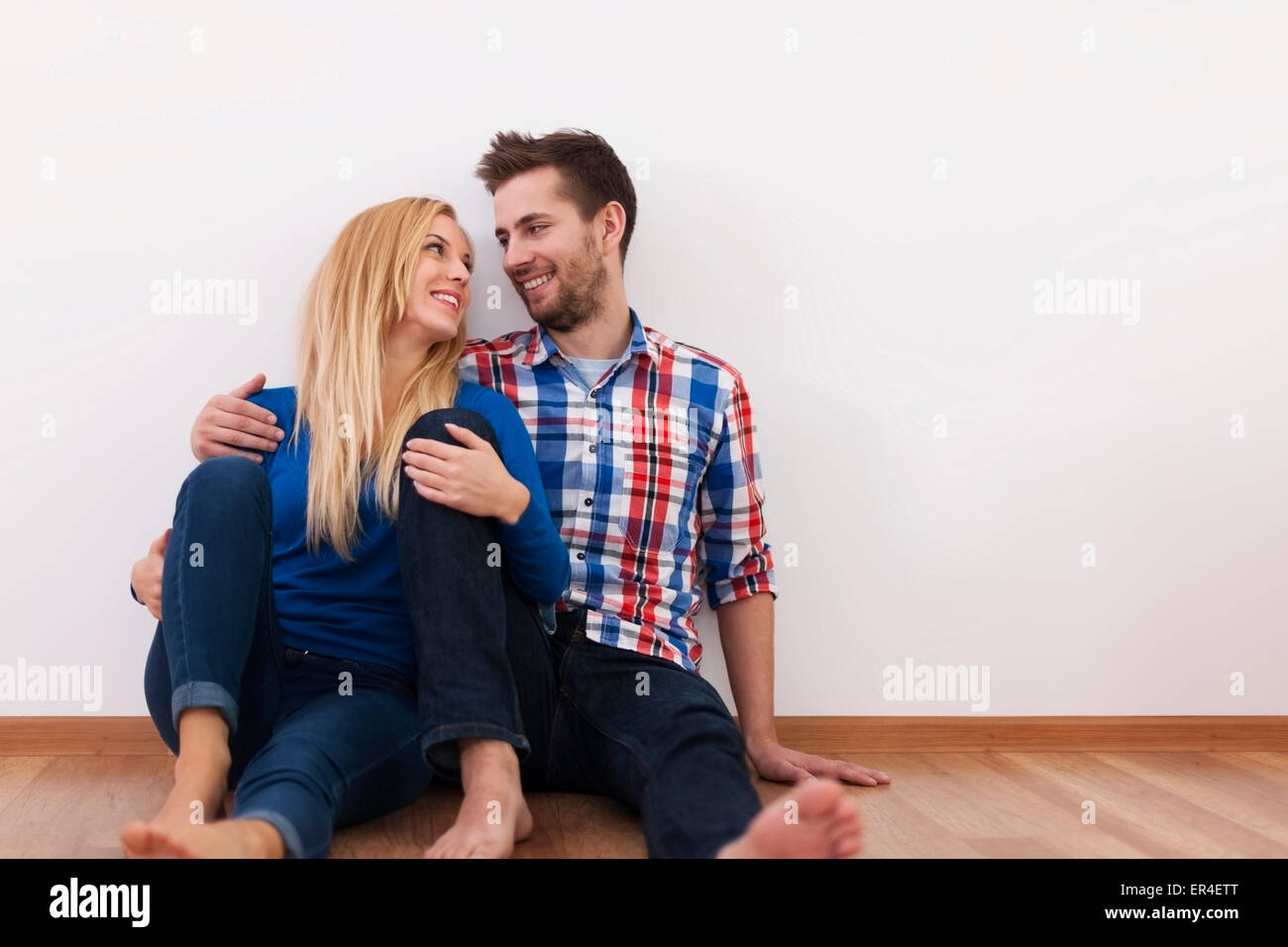 Flirting couple sitting on hardwood floor Stock Photo - Alamy