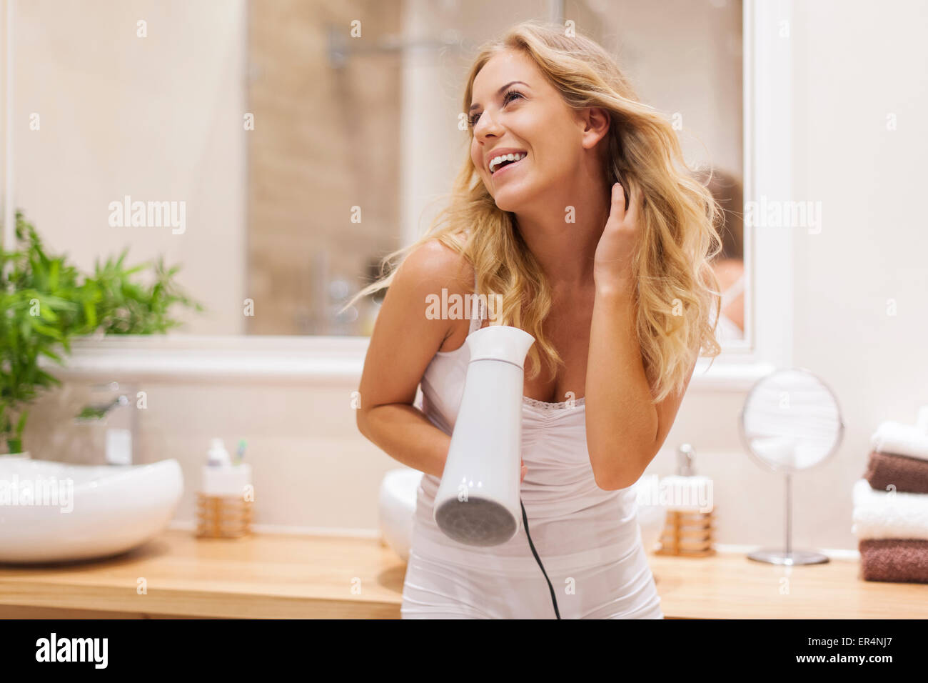 Beautiful blonde woman drying hair in bathroom. Debica, Poland Stock ...