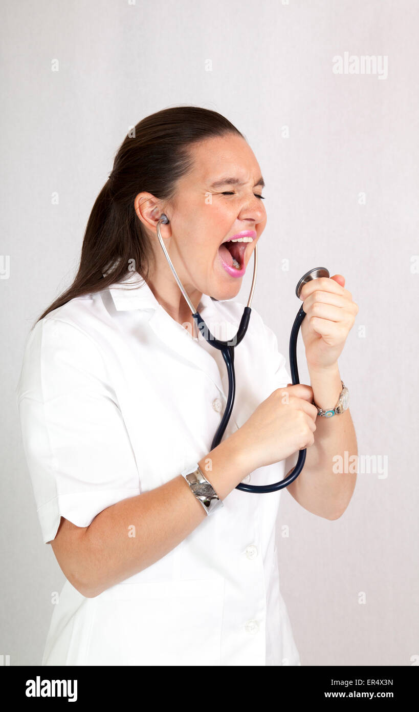 Attractive young female doctor singing to her stethoscope, space for ...