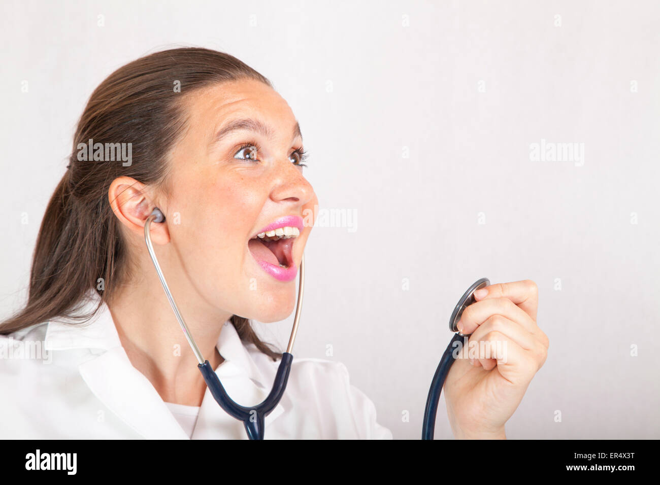 Attractive young female doctor singing to her stethoscope, space for ...