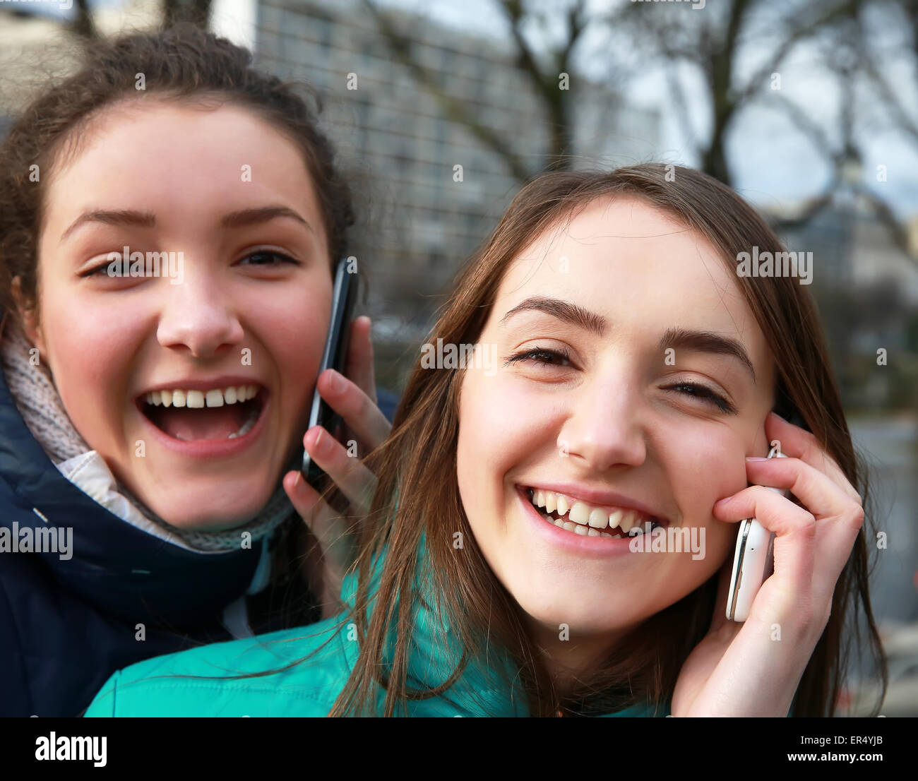 Girls with a mobile phones having fun outside Stock Photo - Alamy