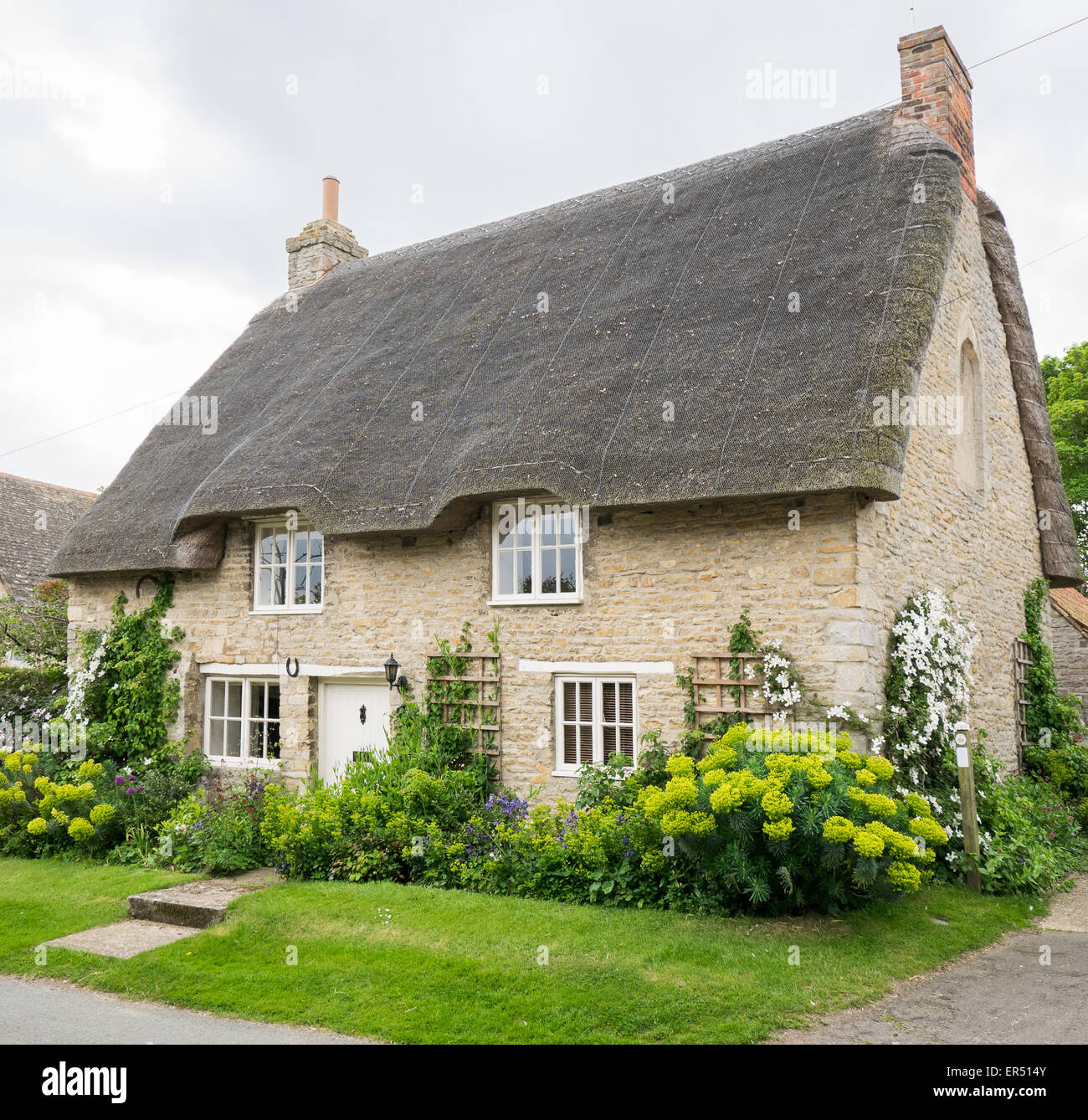 Thatched cottage with a 14th century stone window at the gable end, in ...
