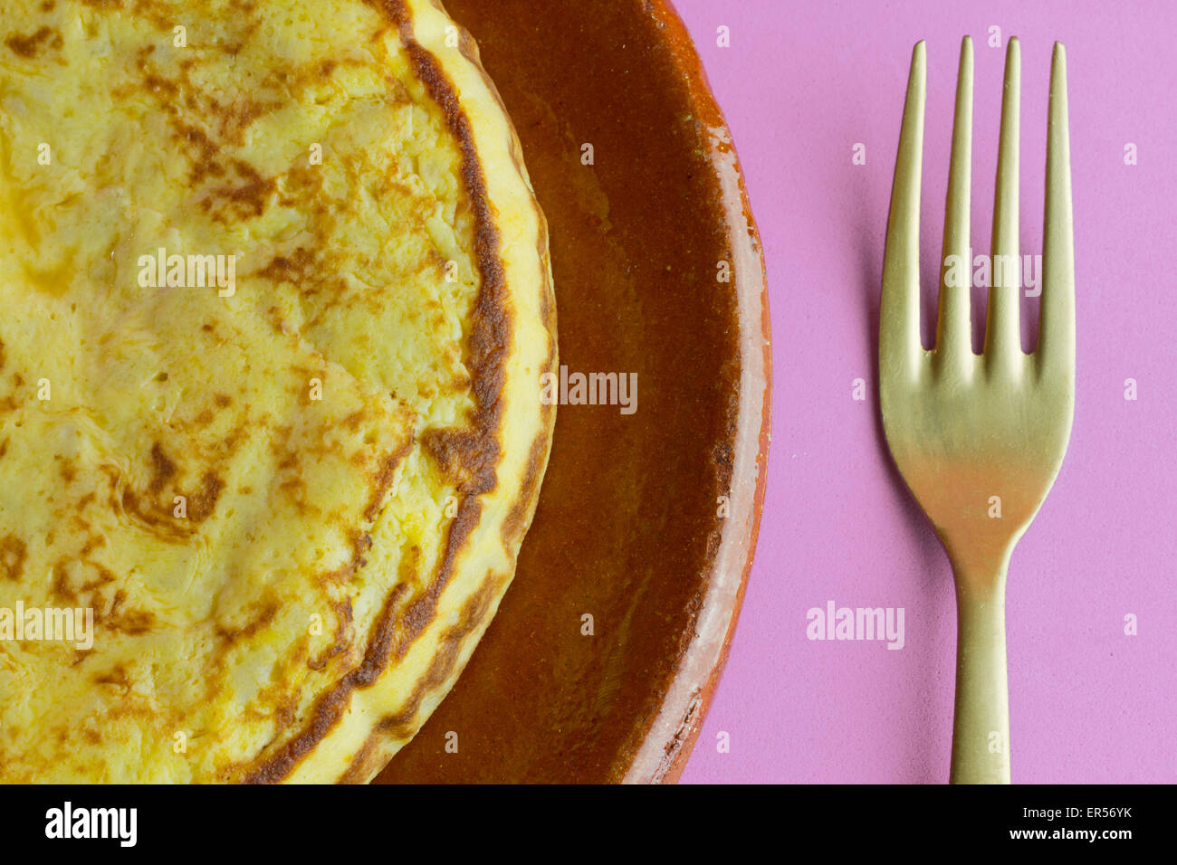 Spanish omelette and golden fork on pink background Stock Photo - Alamy