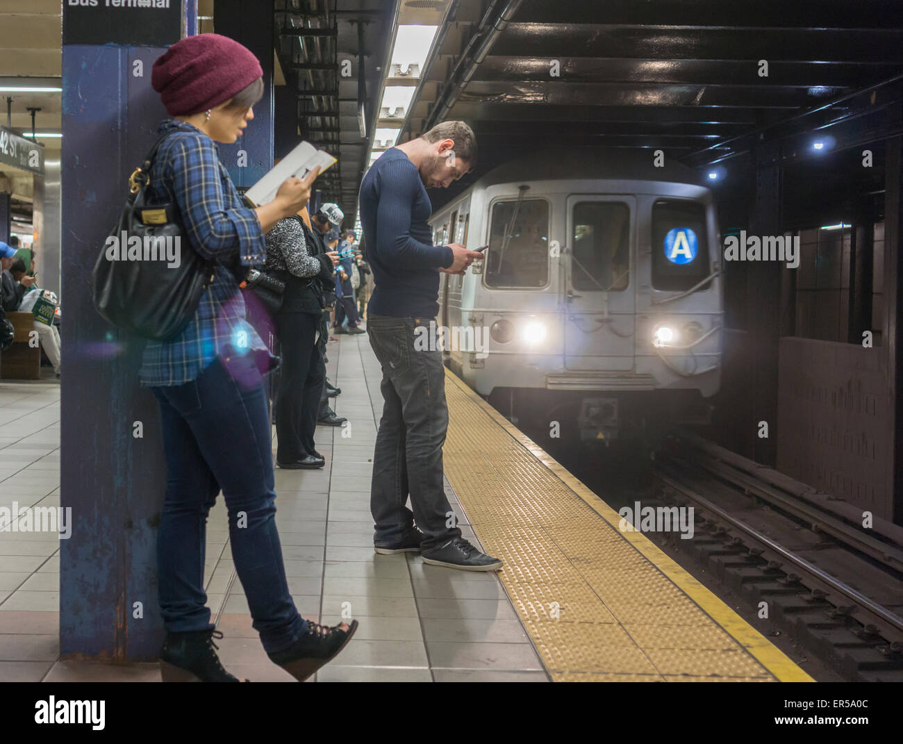 Distracted riders on a subway platform as a train arrives in New York ...
