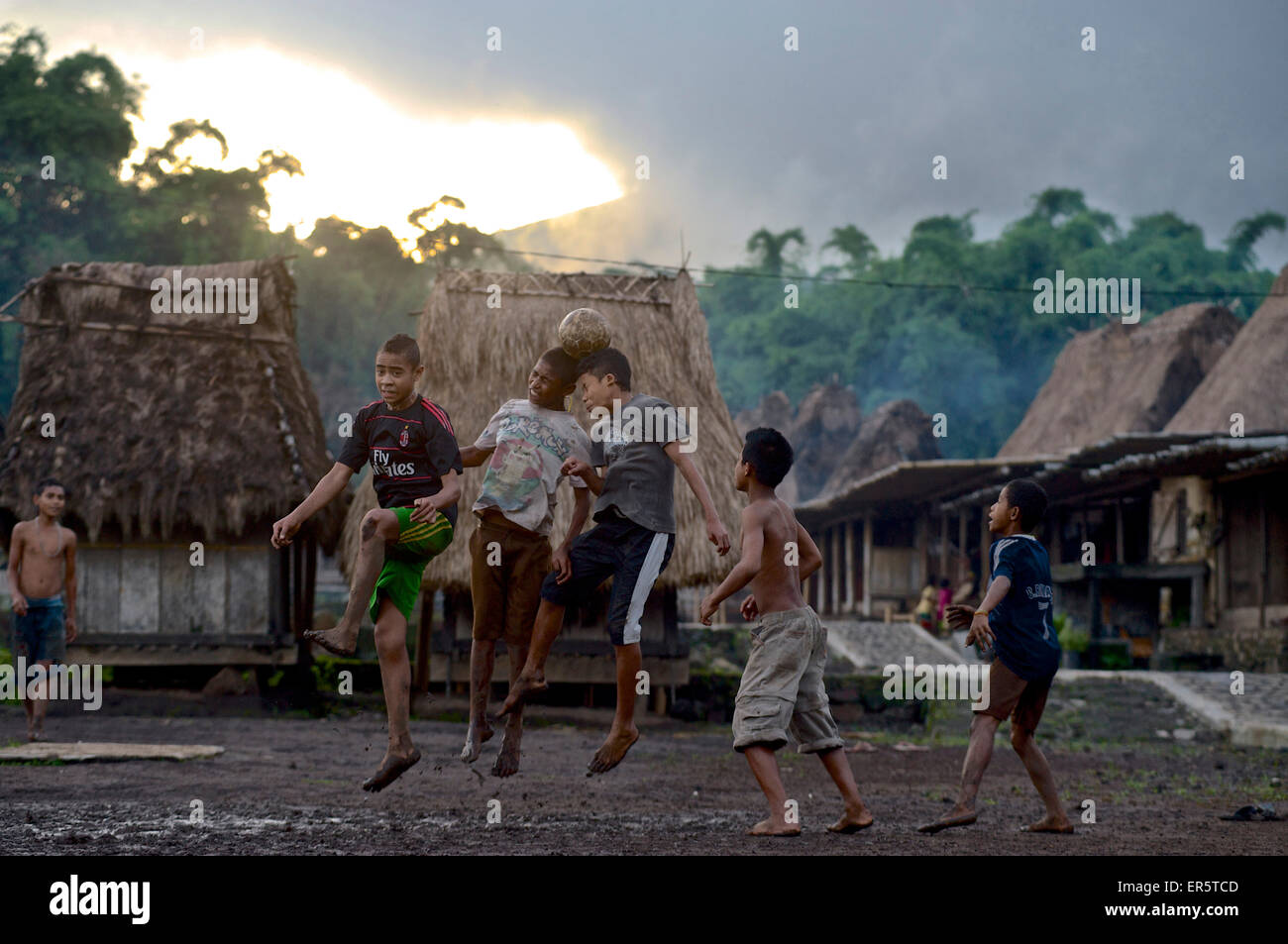 Children playing football on a muddy pitch in a traditional Ngada ...
