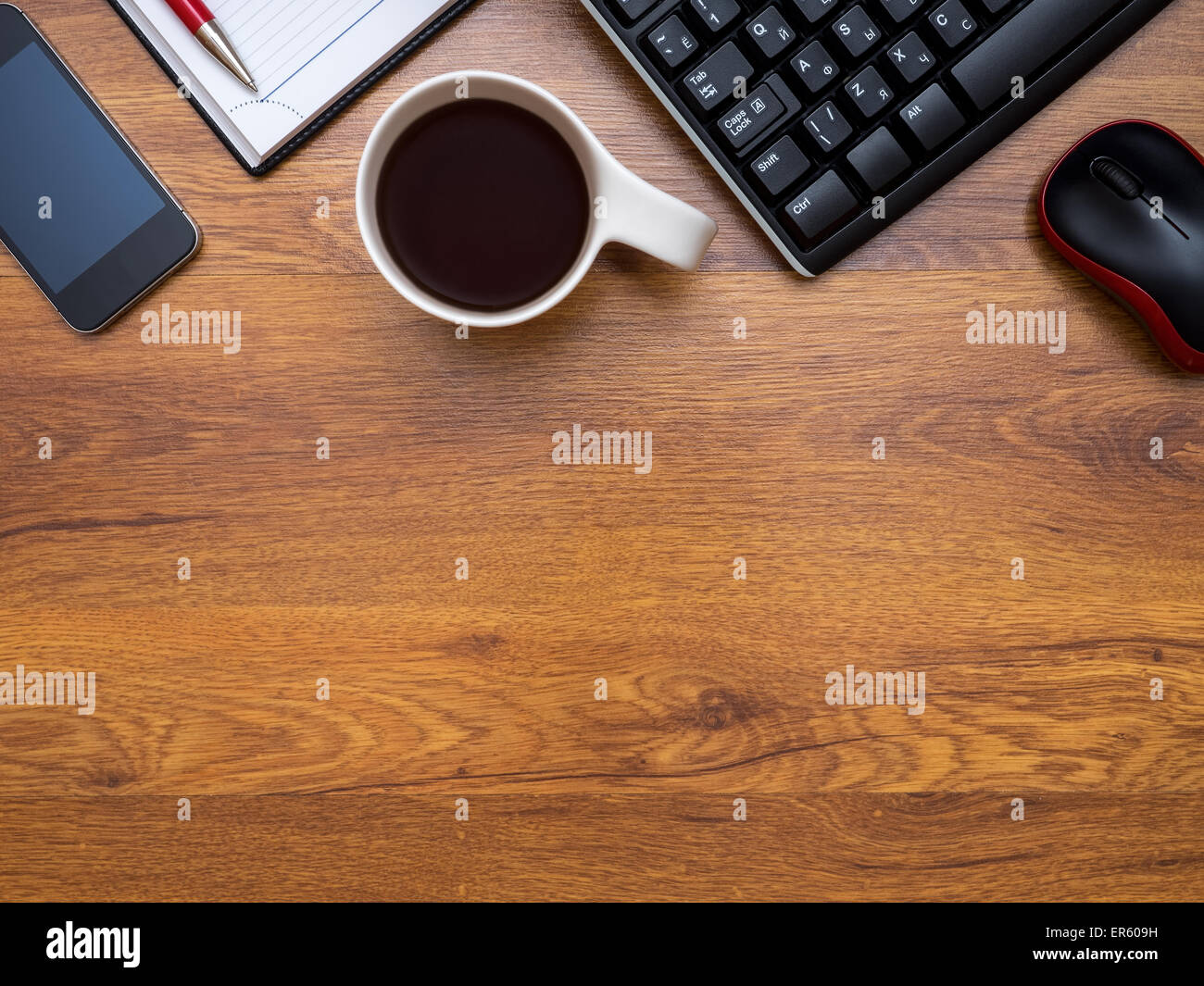 Top view on the desktop with keyboard, phone, notepad, mouse and cup of ...