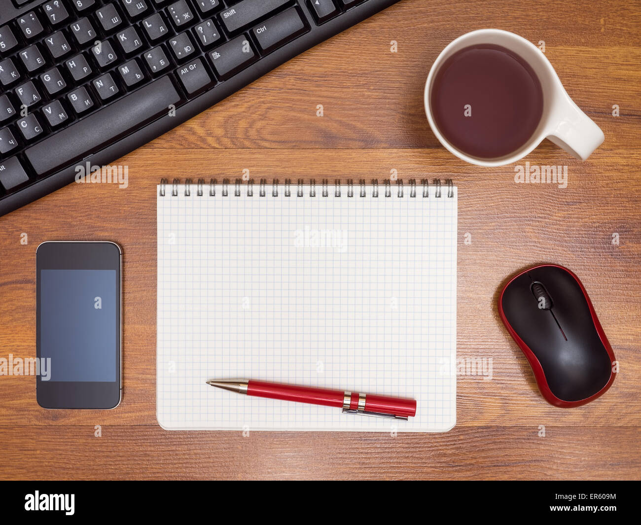 Top view on the desktop with keyboard, phone, notepad, mouse and cup of ...
