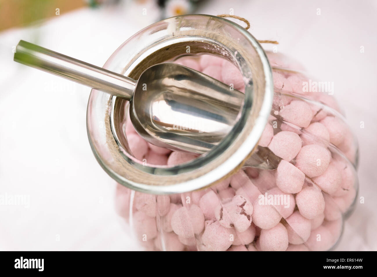 A jar full of Pink bon bon sweets with a scoop. The image has been ...