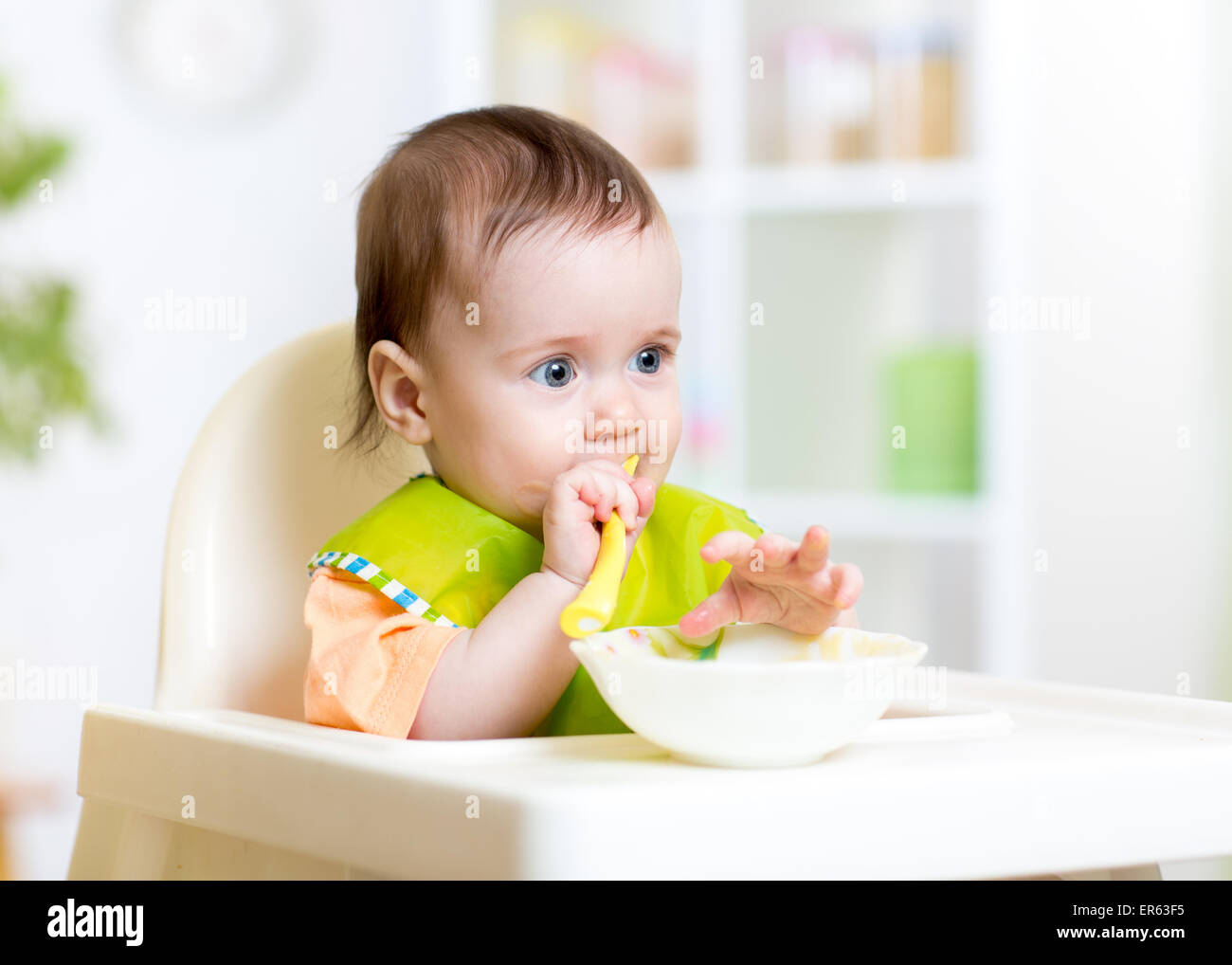 cheerful happy baby child sitting in chair with a spoon Stock Photo - Alamy