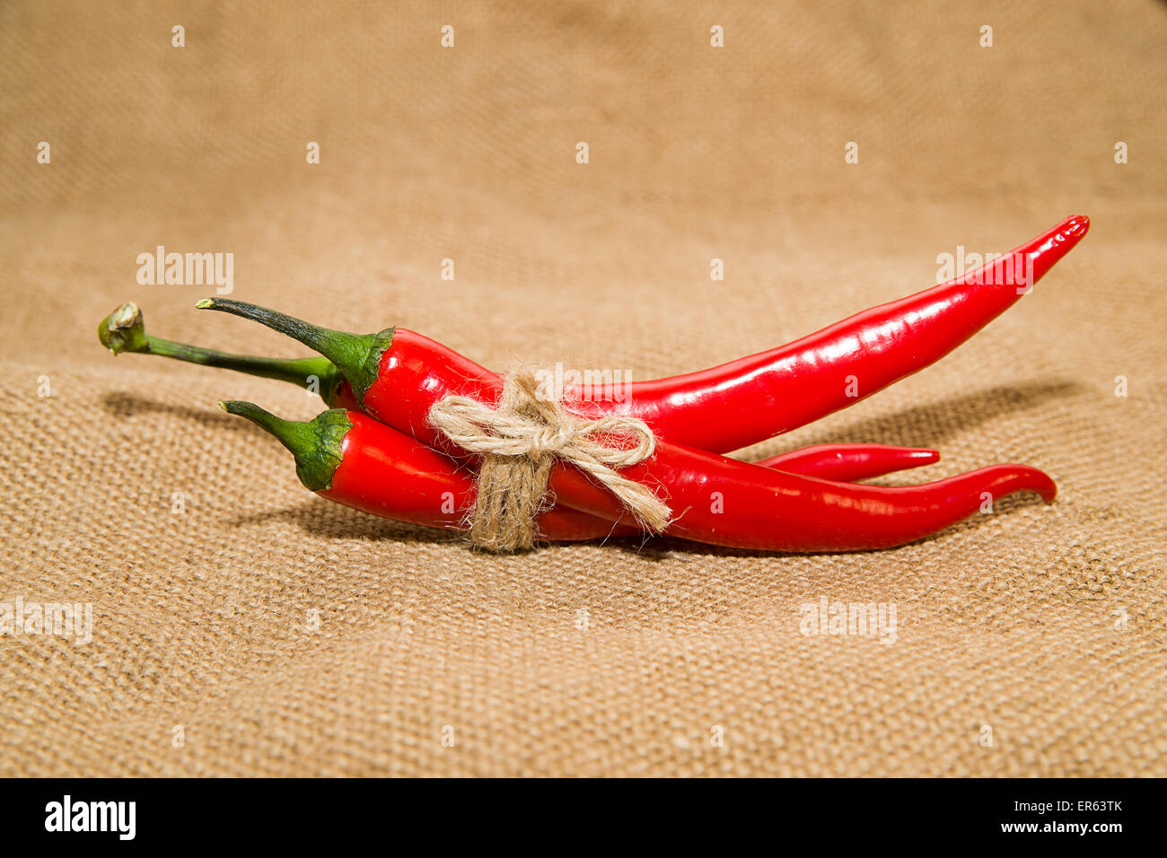 Three Chile peppers tied with a rope on old cloth Stock Photo - Alamy