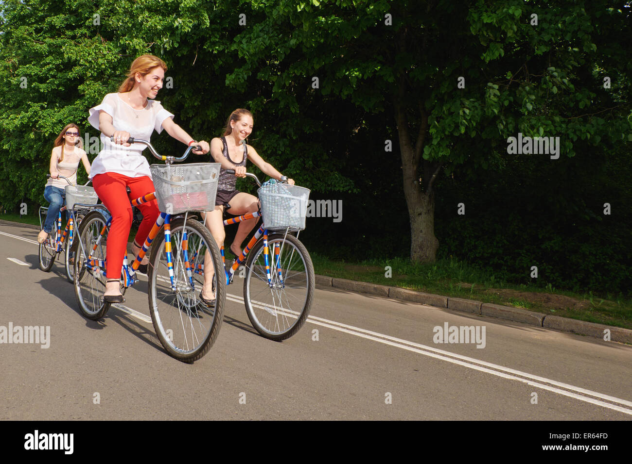 Three young women riding bicycles and smiling Stock Photo - Alamy