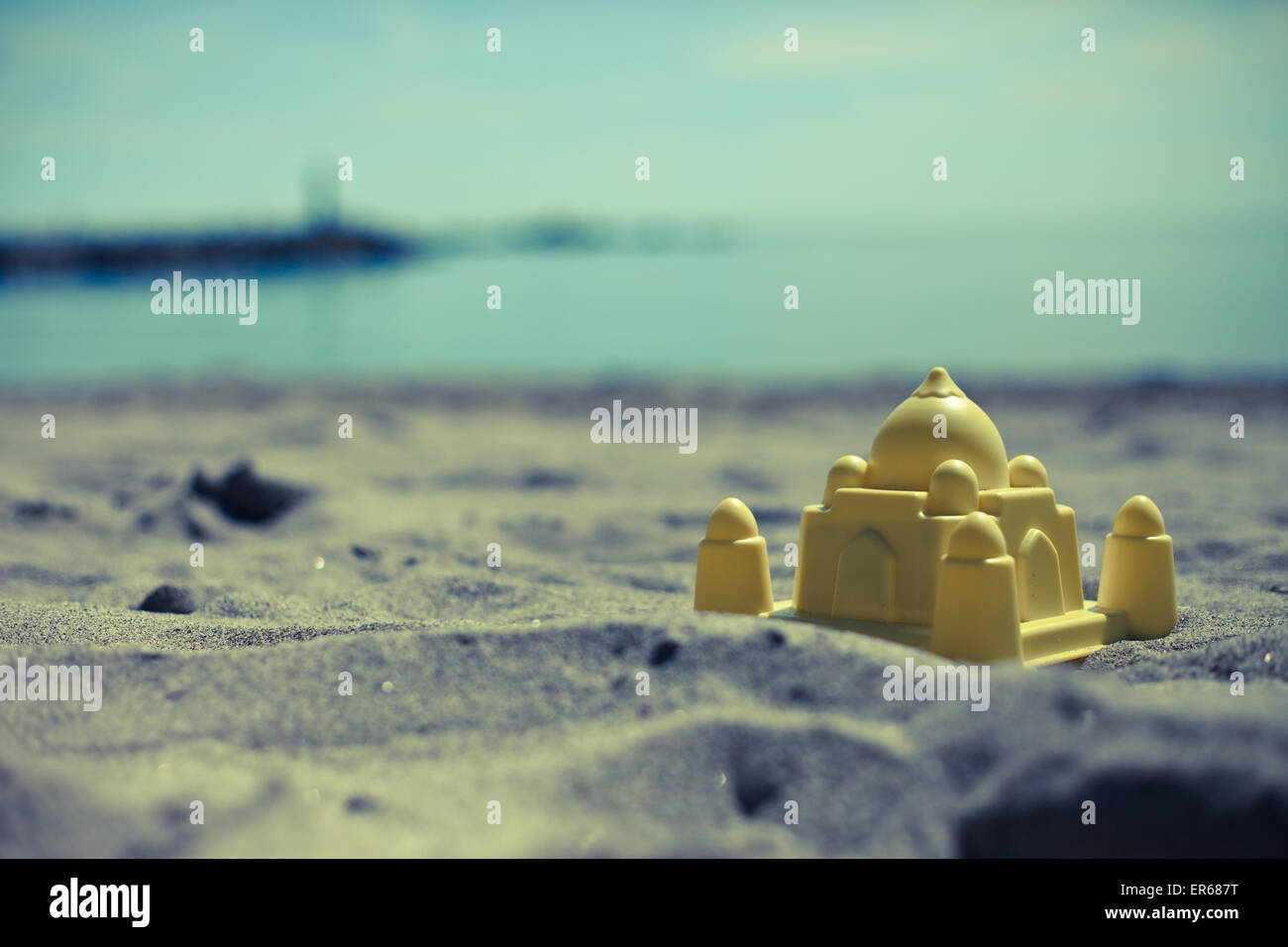 A sandcastle mold in the sand, on the beach, with the water in the ...