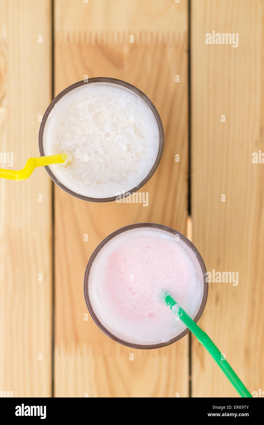 Two Glasses of Milk Shake with straws on Wooden Table. Top view image ...