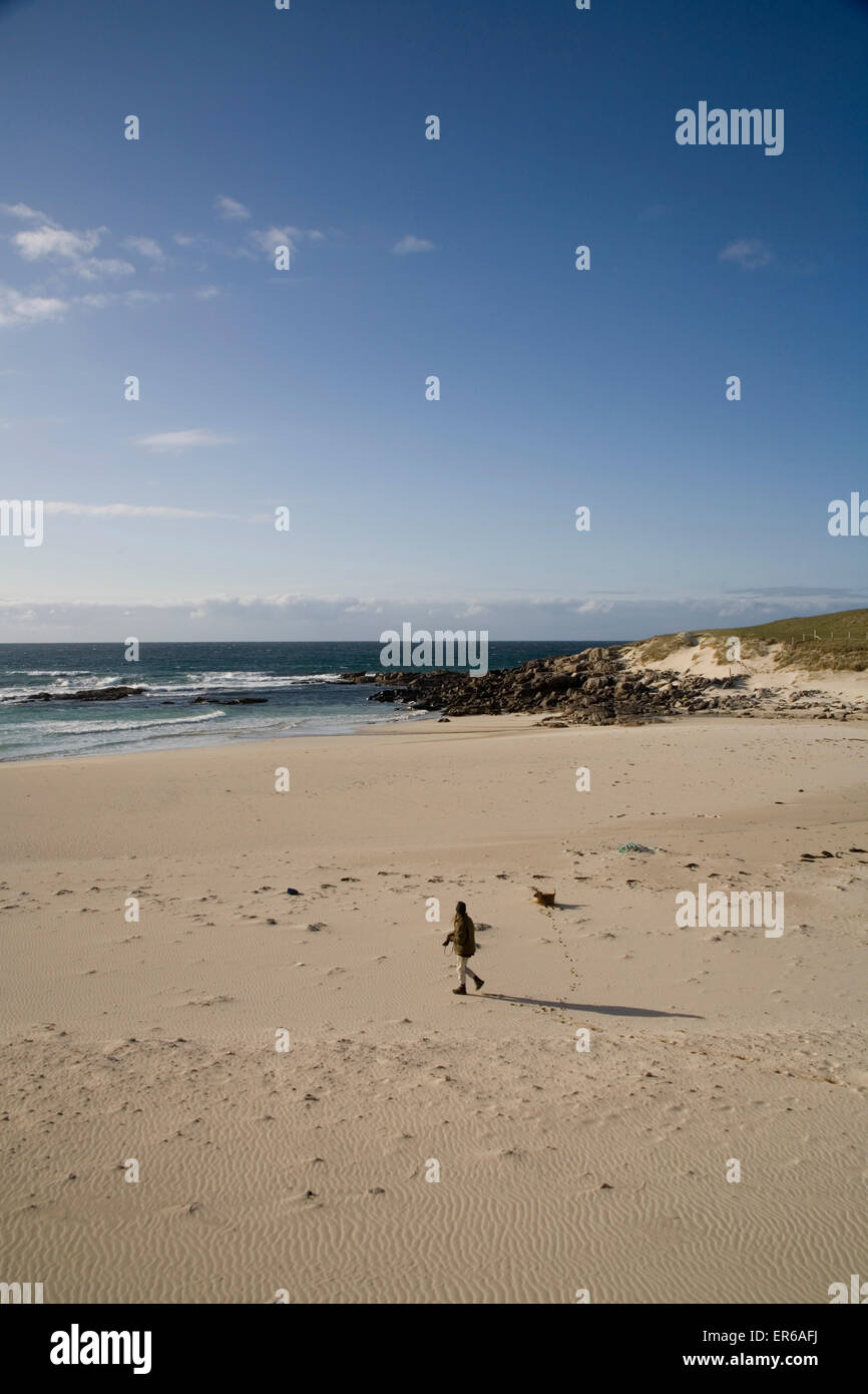 Woman walks her dog across Hosta Beach, North Uist, the Outer Hebrides ...