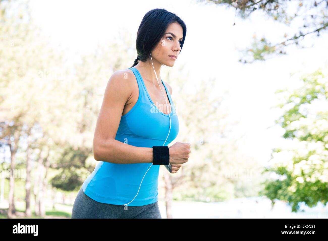 Charming sporty woman in headphones running outdoors in park Stock ...