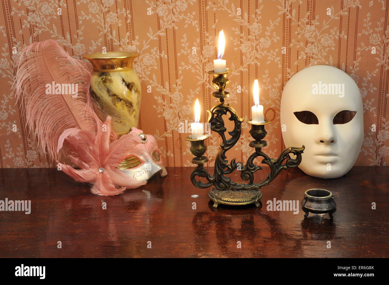 Elegant still life with bronze candelabra, antique goblet and two masks ...