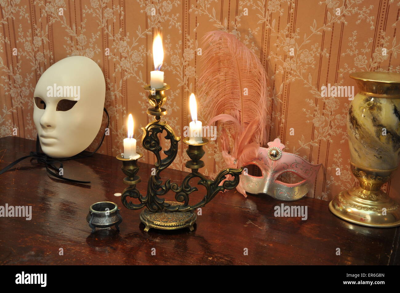 Elegant still life with bronze candelabra, antique goblet and two masks ...