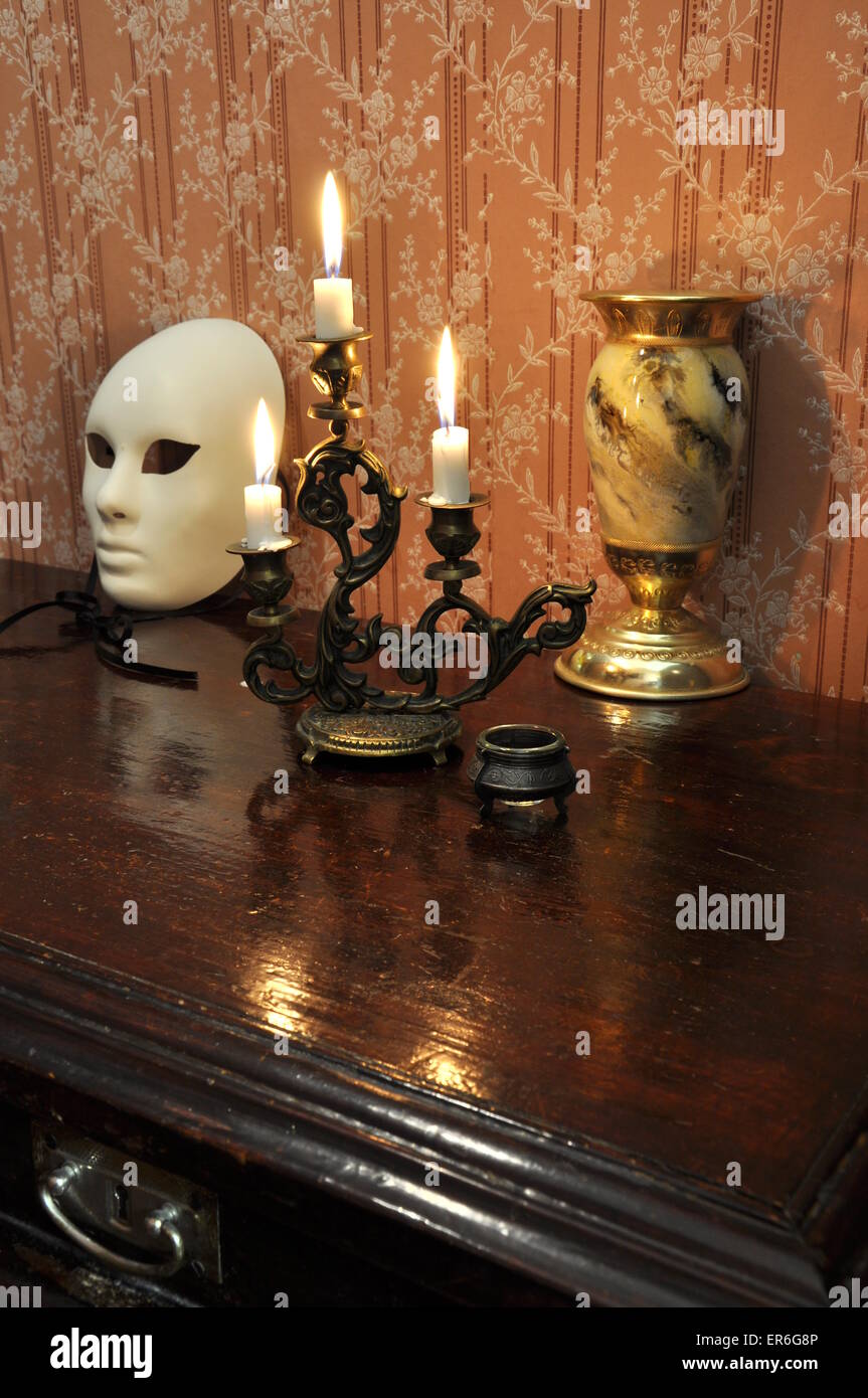 Elegant still life with bronze candelabra, antique goblet and a mask on ...