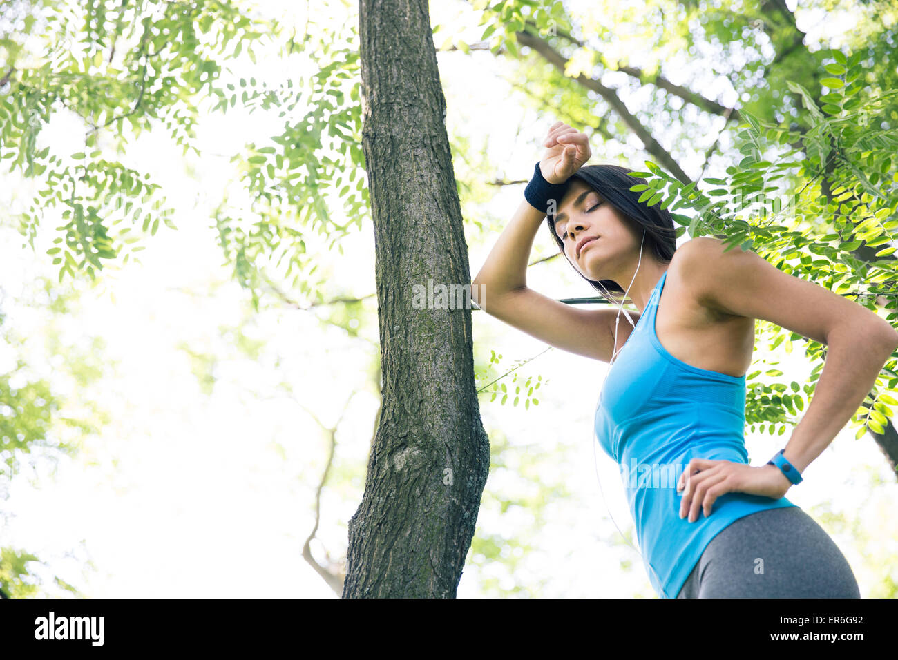 Tired fitness woman resting outdoors in park. Leaning on the tree Stock ...