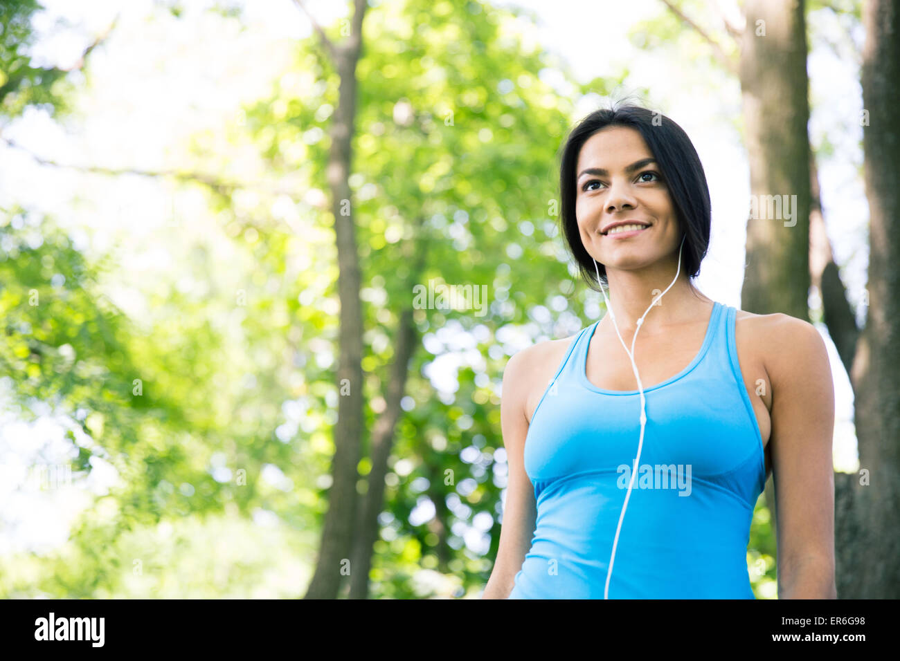 Smiling sports woman in headphones outdoors. looking away Stock Photo ...