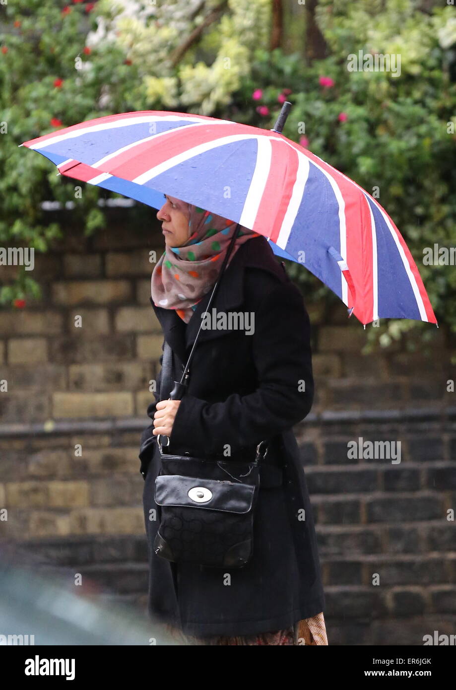 A woman shelters from torrential rain under a Union Jack umbrella ...