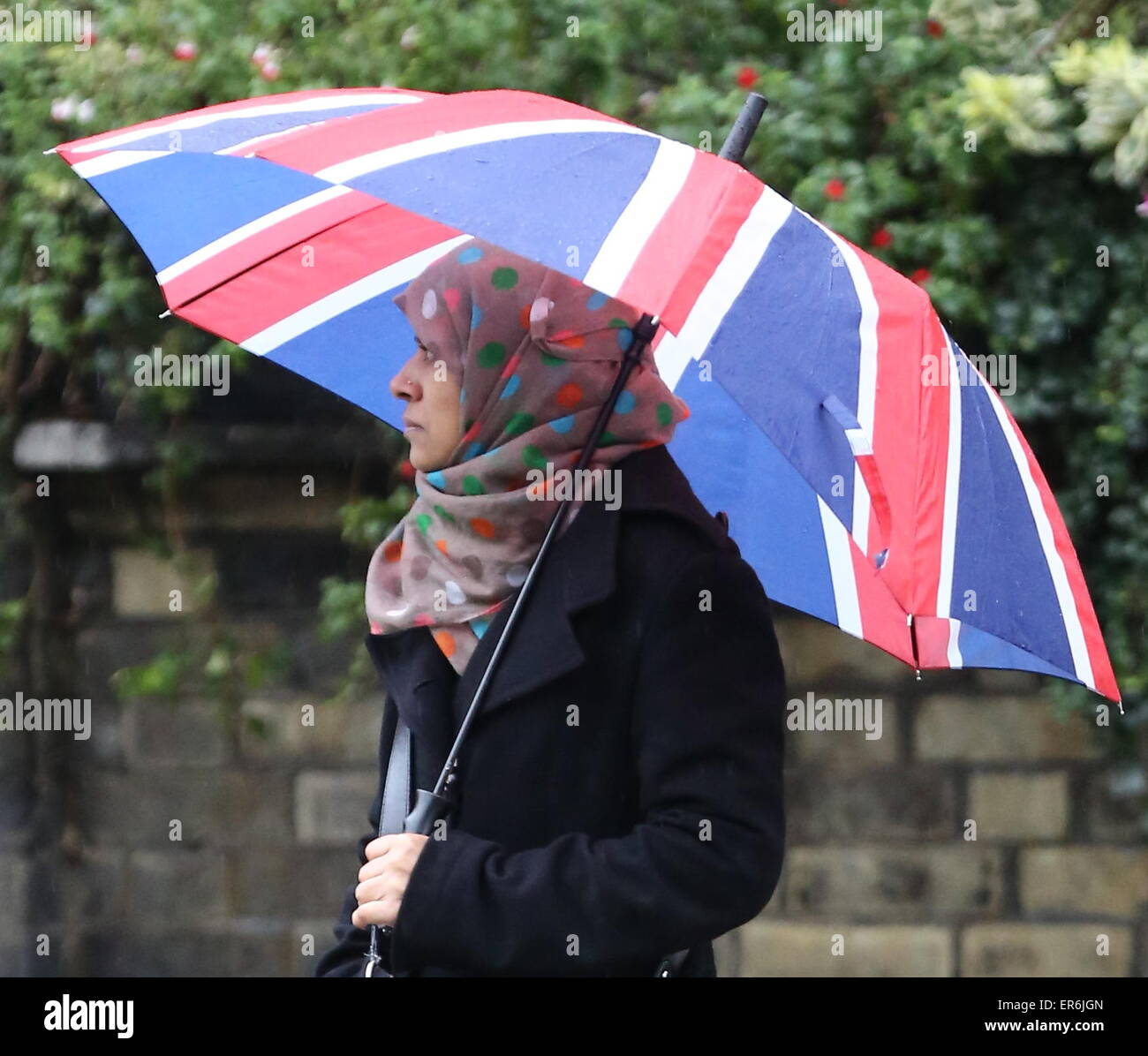 A woman shelters from torrential rain under a Union Jack umbrella ...