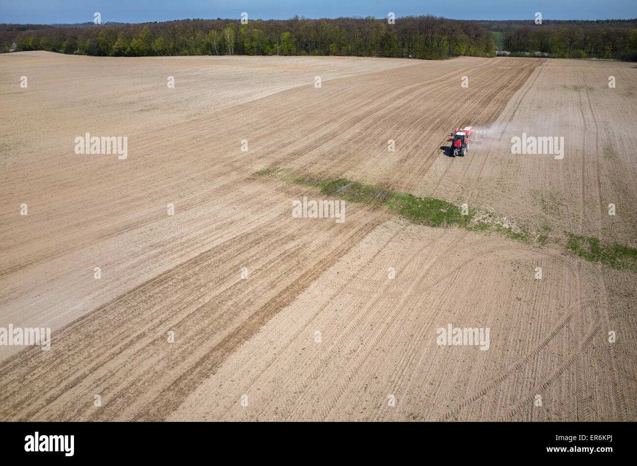 Aerial view of the the tractor harrowing the large brown field in ...