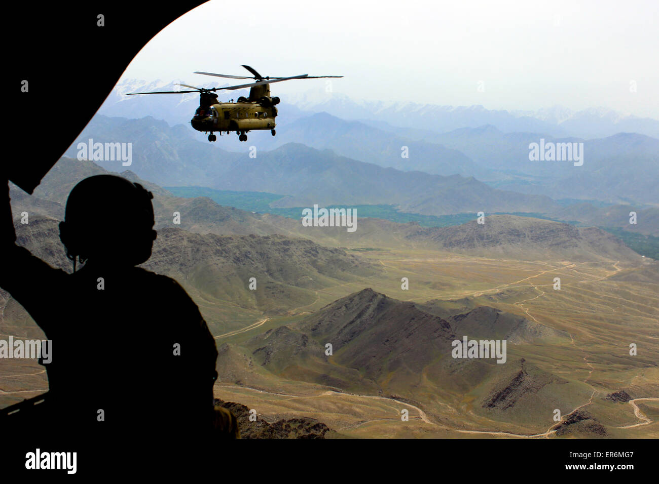 A US soldier scans the group while sitting on the ramp of a CH-47 ...