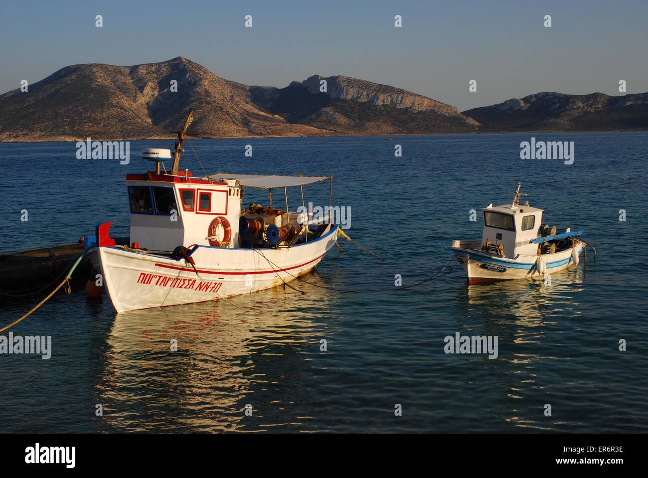 Small fishing boats in shimmering evening sunlight on the Greek Island ...