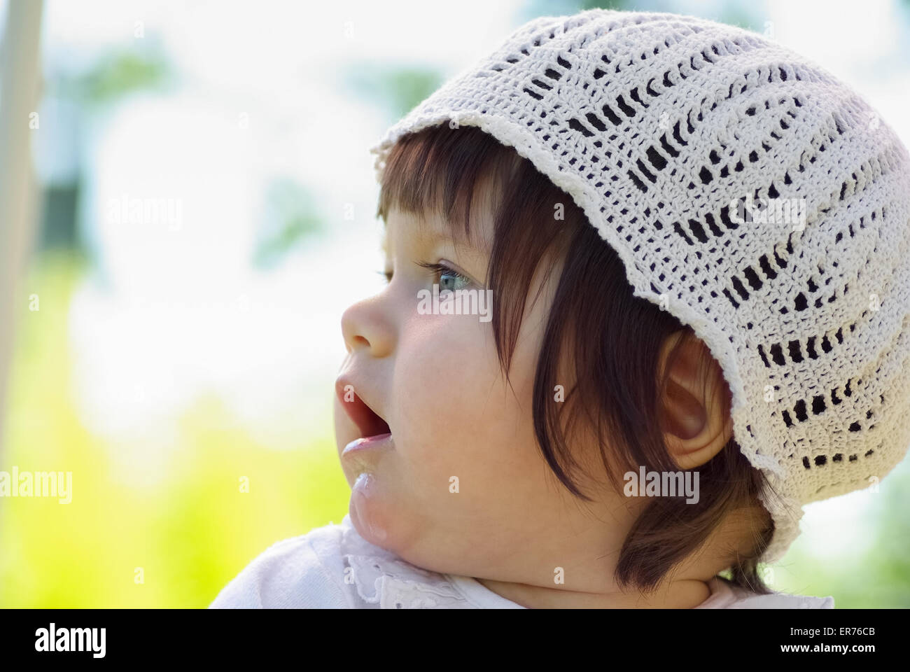 Baby in a white knitted cap outdoor close-up. Photo of a little girl in ...