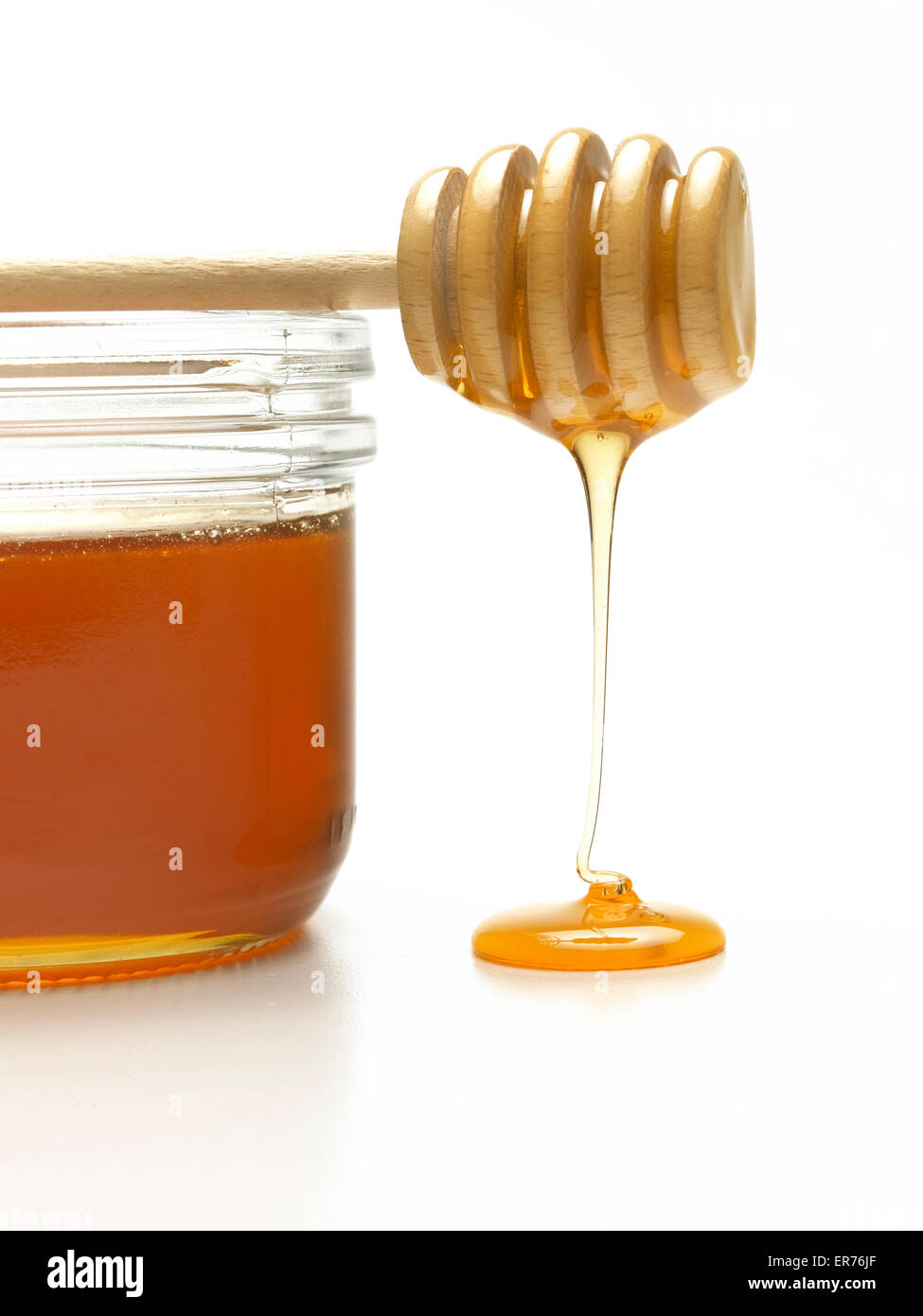 Honey dipper with drip onto a white kitchen tabletop Stock Photo - Alamy