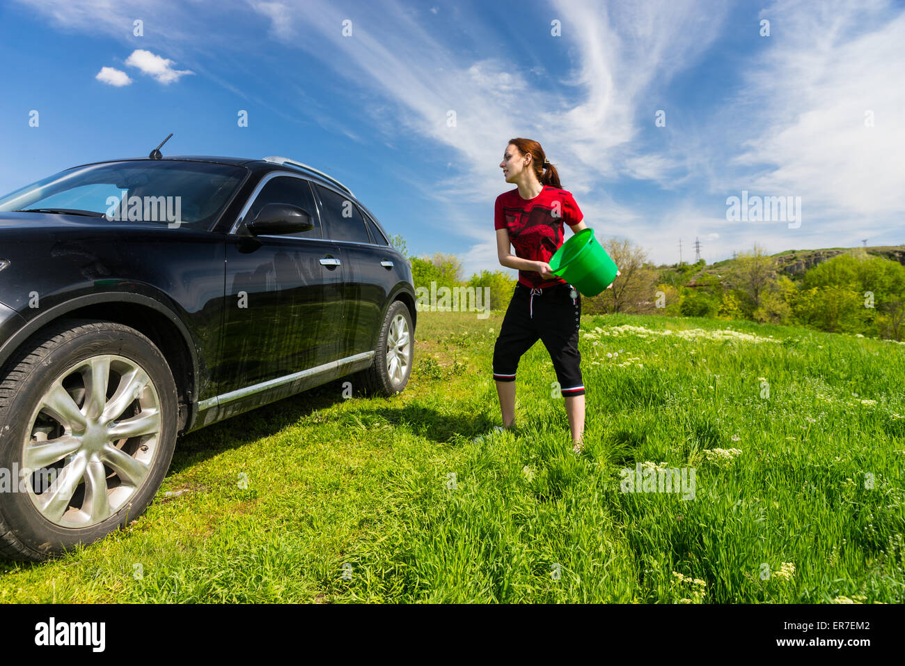 Young Woman Washing Black Luxury Vehicle in Grassy Green Field on ...
