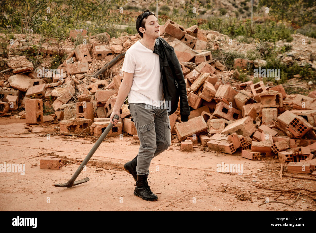 Exhausted guy pulling a pickaxe on a construction site Stock Photo - Alamy