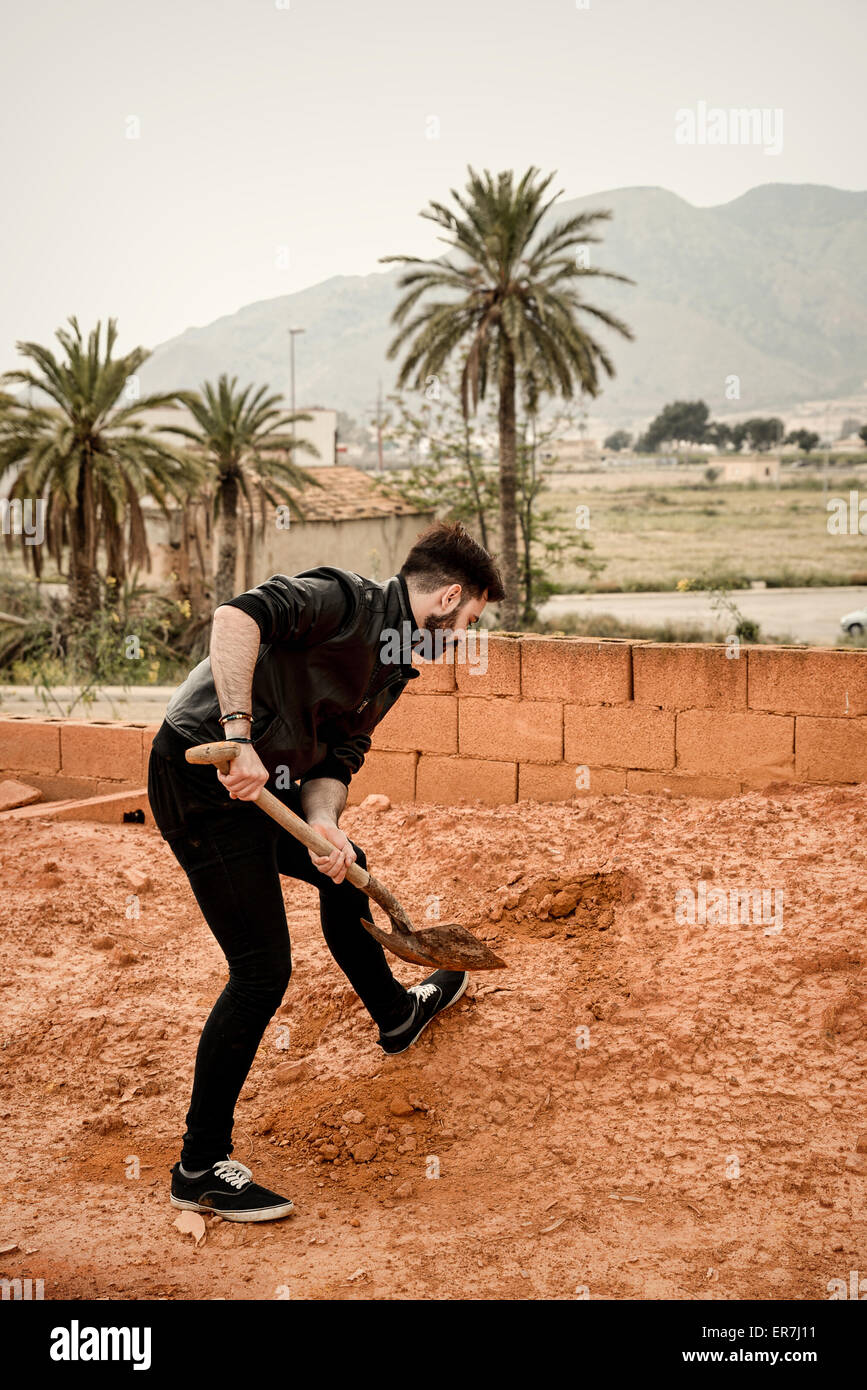 Guy moving earth with a shovel on a demolition site Stock Photo - Alamy