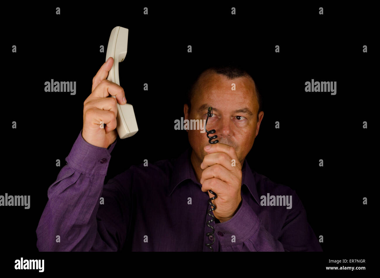 Man trying to connect a telephone with a bewildered look on his face ...