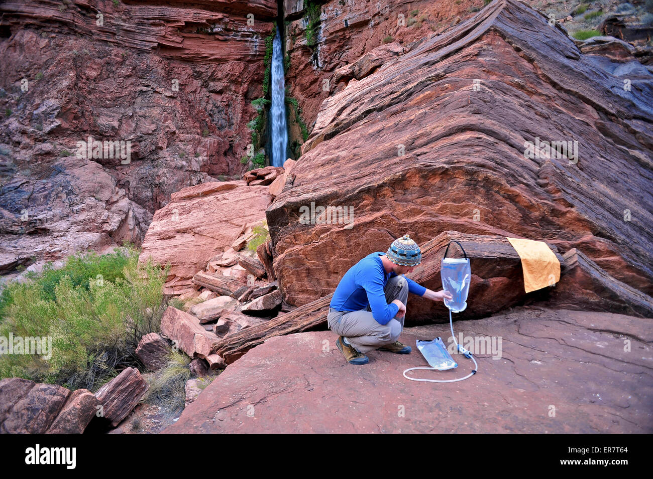 Male hiker filters water on a cliff-pinched patio near Deer Creek Falls ...