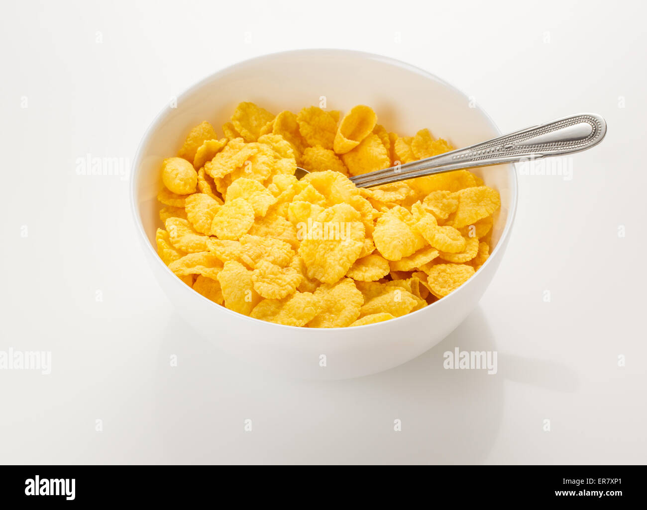 Yellow corn flakes in white bowl with spoon Stock Photo - Alamy