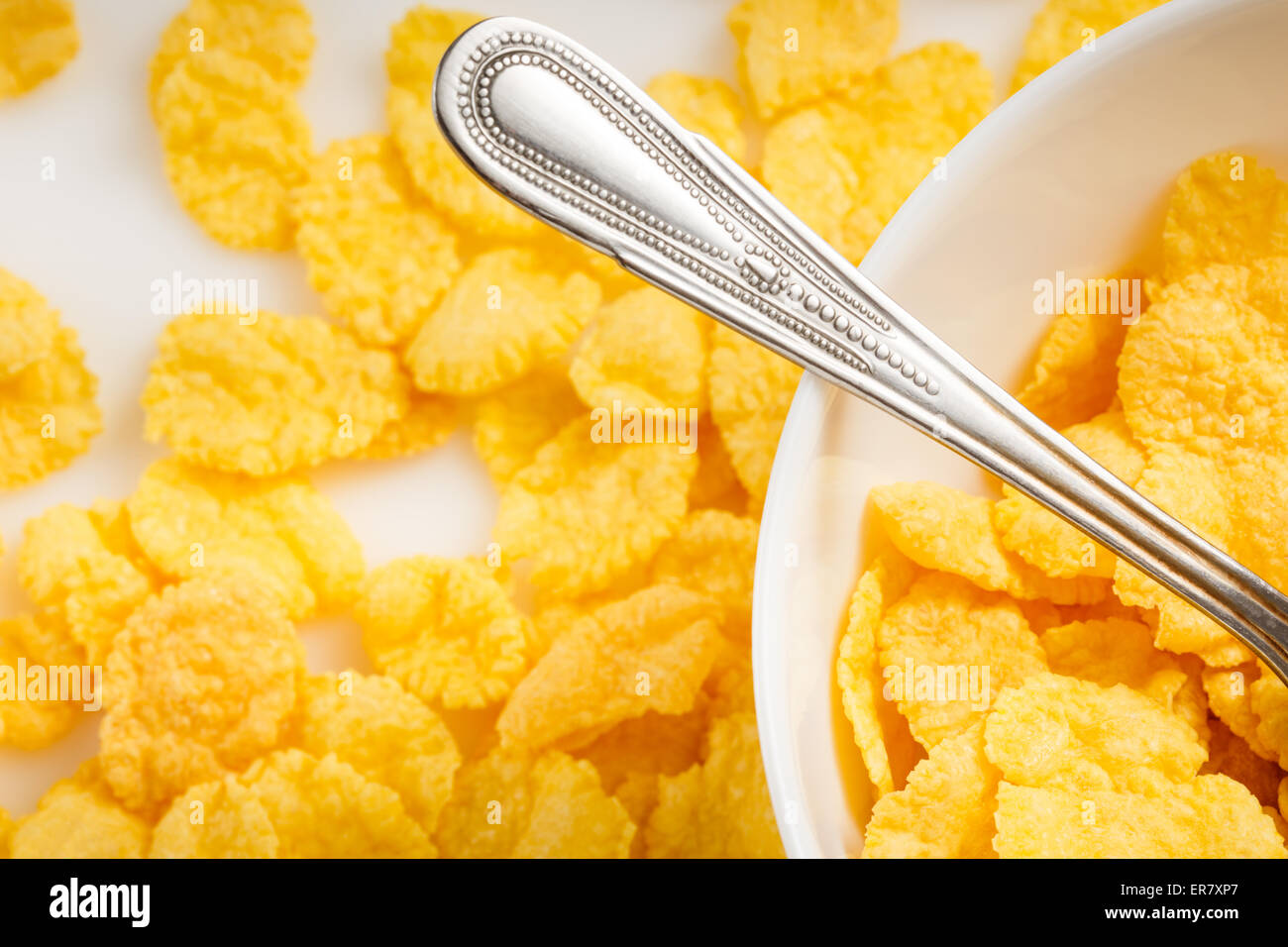 Yellow corn flakes in white bowl with spoon Stock Photo - Alamy